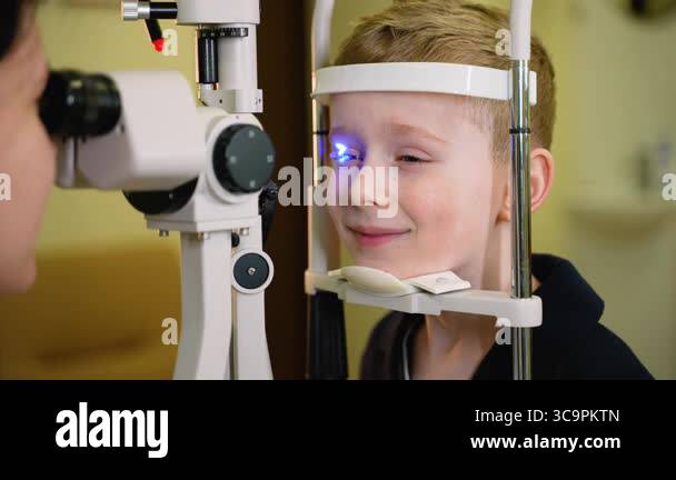 Ophthalmologist examining a childs eye with a slit lamp, a diagnostic ...
