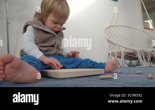 Joyful toddler plays game with wooden sticks, solitaire game. Baby ...