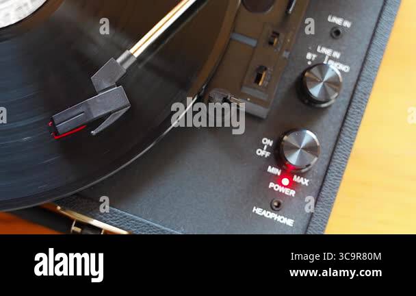 Close-up of record player needle tracking vinyl grooves during playback ...