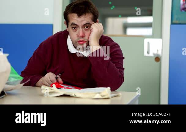 Adult male with a mental disability sits alone at a table in a mental ...