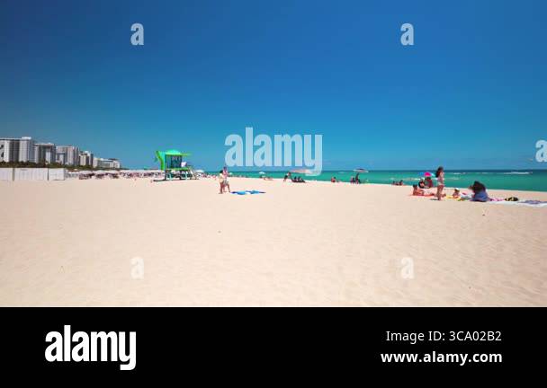 Tourists sunbathing on sandy Miami Beach with emerald green water and ...