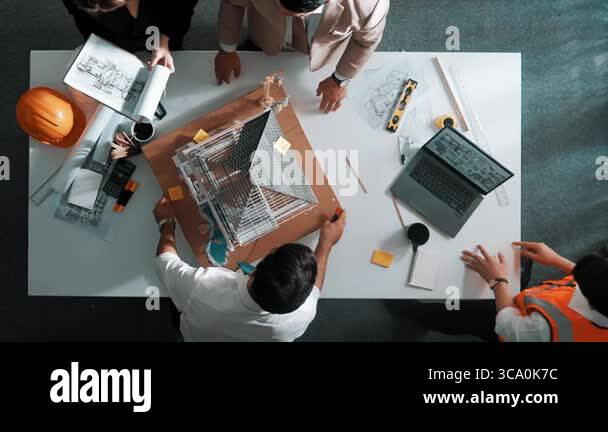 Top down aerial view of smart architect engineer team inspect house model while manager hold ...