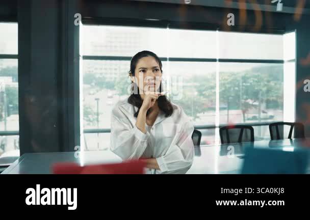 Beautiful female leader thinking about start up project in front of glass board. Smiling young ...