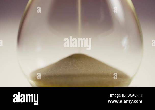 Close up of sand timer clock with sand flowing from through hourglass ...