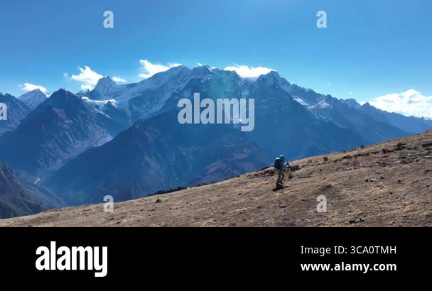 Backpacking woman climbing up on steep cliff edge at high altitude ...