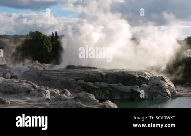 A geothermal landscape featuring steam rising from hot springs ...