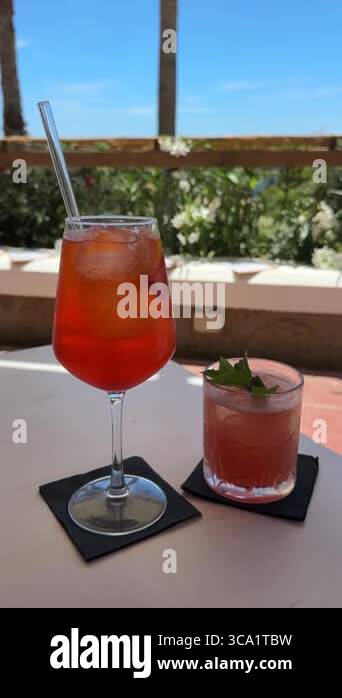 Refreshing summer cocktails on a sunny terrace with tropical plants and ...