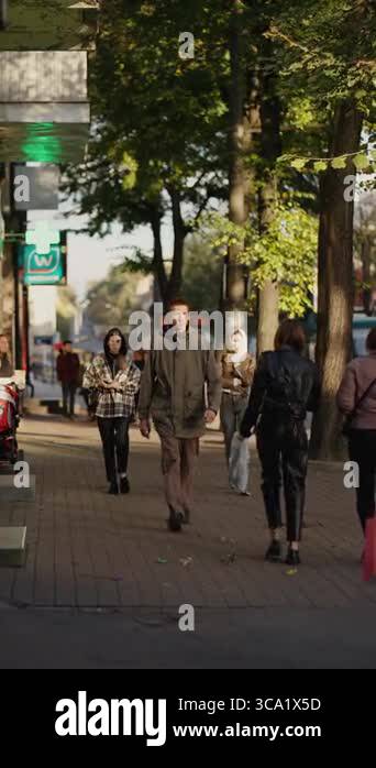 People walking on a city sidewalk in the evening sun, city life with ...