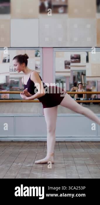 In dancing hall, Young ballerina in black leotard performs grand ...