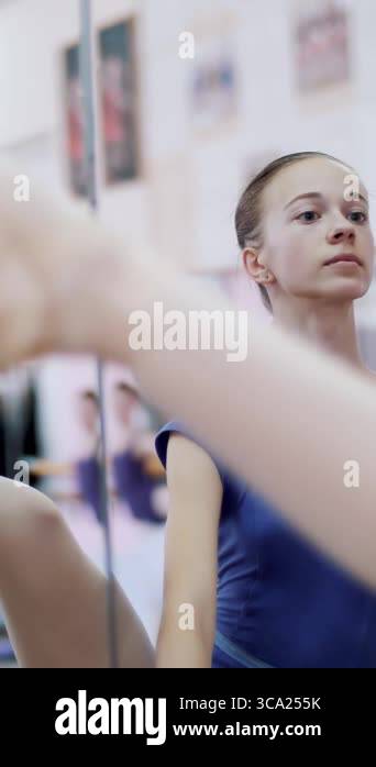 In dancing hall, Young ballerina in purple leotard performs developpe ...