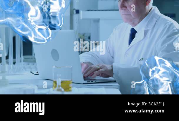 Senior male researcher typing on silver laptop in technology lab, with ...