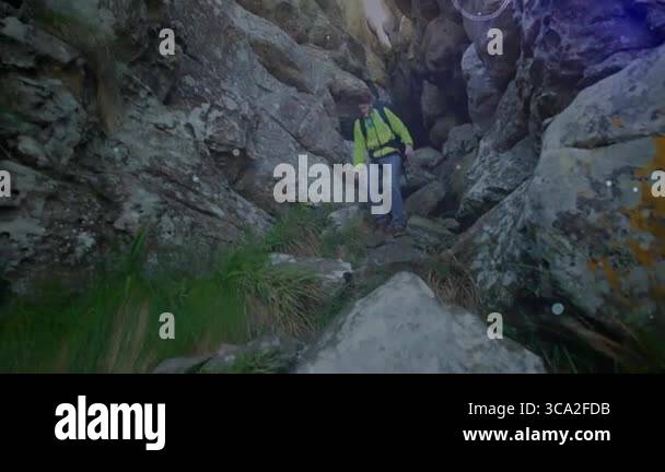 Male hiker descending rocky mountain pass, under digital navigation overlay for outdoor ...