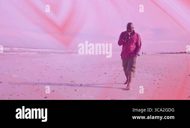 Senior man walking barefoot along beach, viewing animated finance graph ...