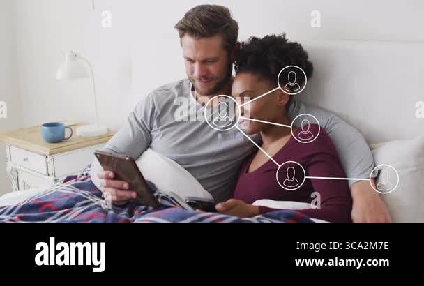 Couple tapping tablet on bed engaging technology content while ...