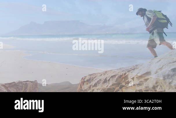 Male hiker stepping across sunlit coastal rocks, with animated map ...