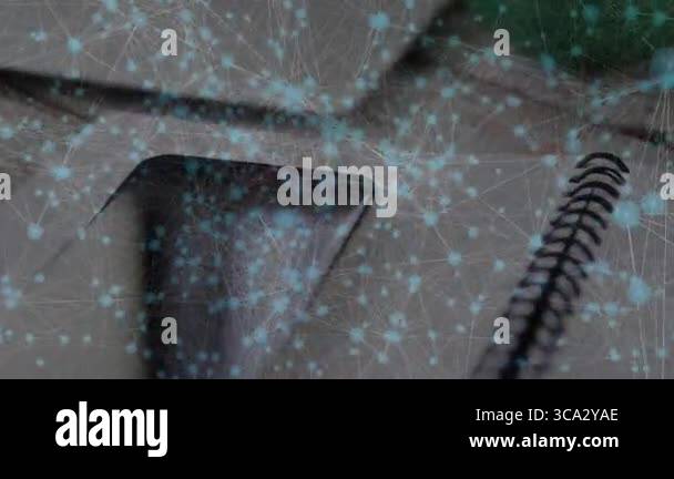 Data network flowing across silver laptop keyboard and smartphone on white-washed wooden ...