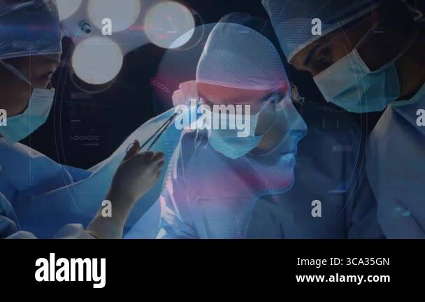 Surgeons operating in operating room under surgical lights, with ...