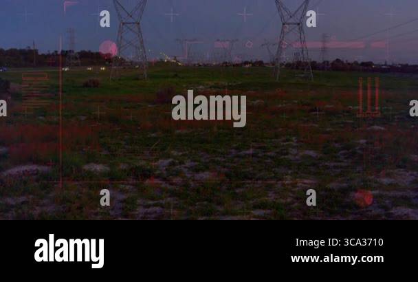 Transmission towers carrying power lines across grassy dusk field ...