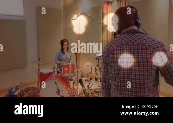 Woman drummer sitting at red drum kit in recording studio, with ...