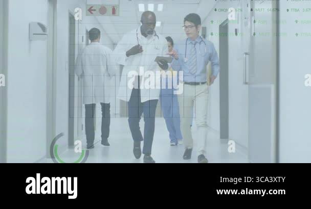 Doctors walking and discussing with tablet in hospital corridor ...