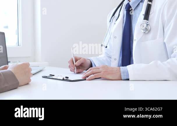 Doctor man taking notes while listening to a female patient explaining ...