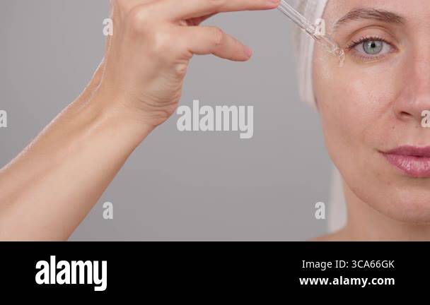Close-up portrait of half calm female face, woman applying serum on ...