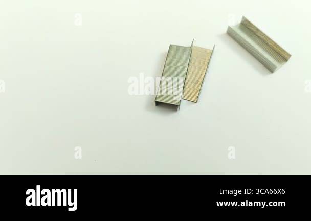 a bunch of staples on a white background. The contents of a stapler are ...