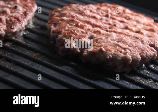 Close-up of juicy burger patty sizzling on hot grill in a modern ...