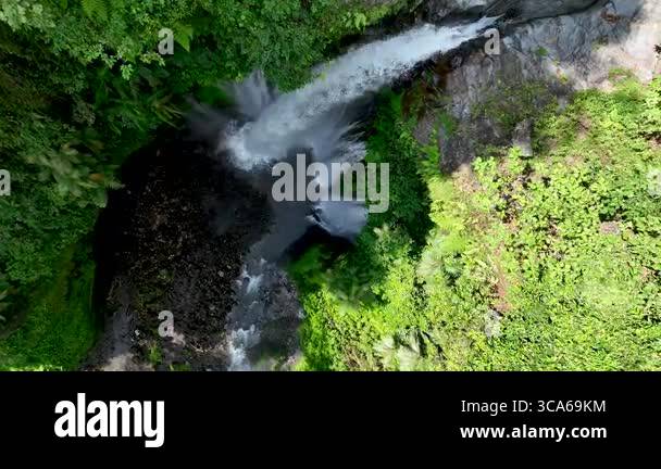 Aerial view of Tiu Kelep waterfall plunging through lush tropical greenery in Lombok. The ...