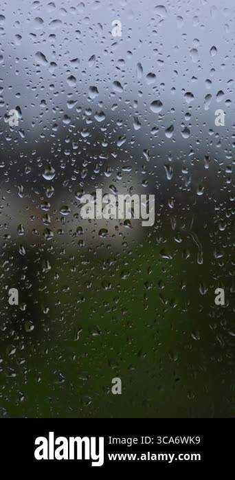Water drops run down the transparent glass. Rain drips on the window ...