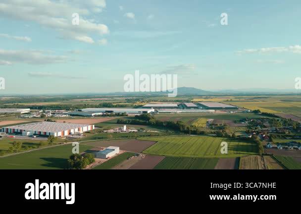 Aerial view of industrial warehouse complex near green agricultural ...