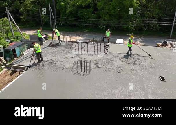 Construction workers pouring and leveling concrete slab. Aerial view of ...