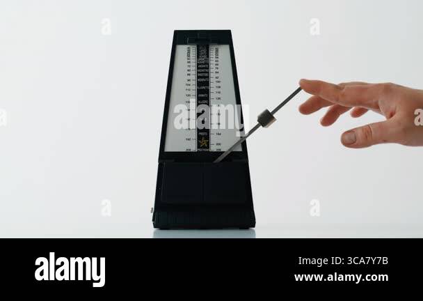 Musician hand adjusting metronome on white desk closeup. Tempo tool ...