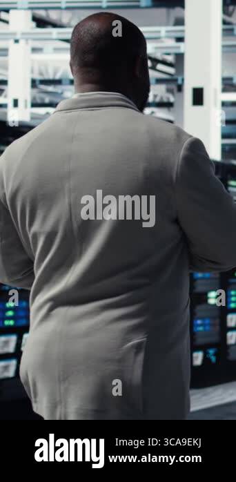 Vertical video Engineer walking in data center using device to ...
