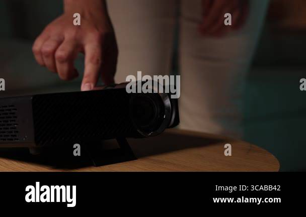 Woman turning on video projector and watching movie at home, selective ...