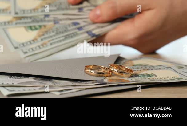 Woman counting dollar banknotes at wooden table, focus on two gold ...