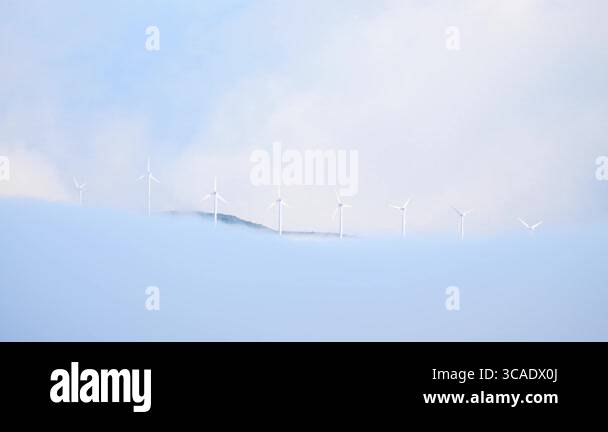 Wind turbines farm on hill in foggy landscape. Windmill covered with ...