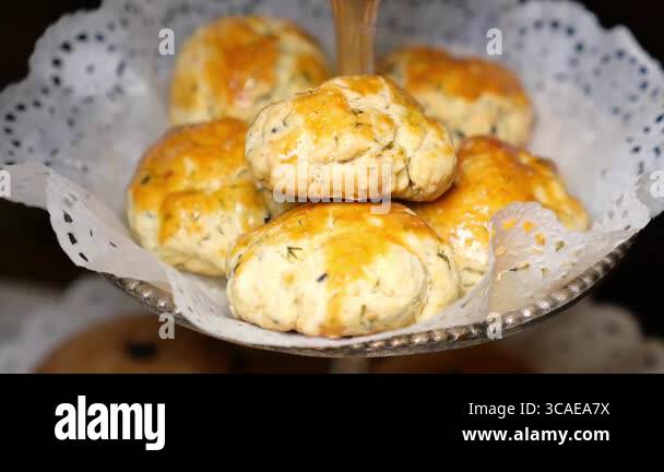 Delicious scones are presented on a silver tray, topped with golden ...