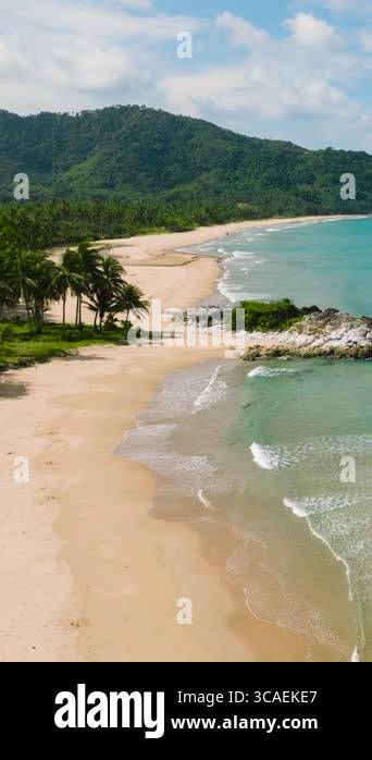 Beautiful ocean waves over sandy beach with palm trees. Duli Beach in ...