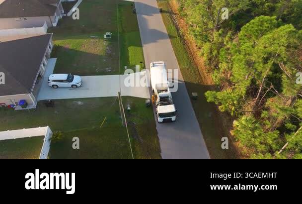 American garbage truck picking up trash bins on rural street side Stock ...
