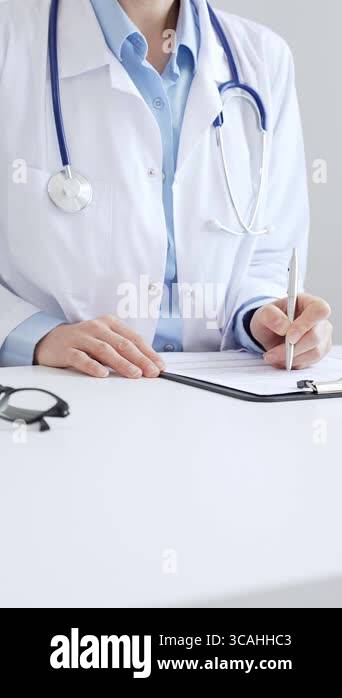Female doctor completing healthcare paperwork, clipboard positioned ...