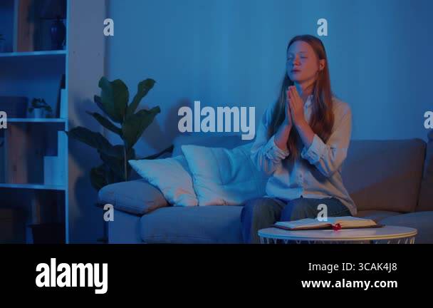 Young Woman Sitting Comfortably on Sofa in Evening Light, Hands Folded ...