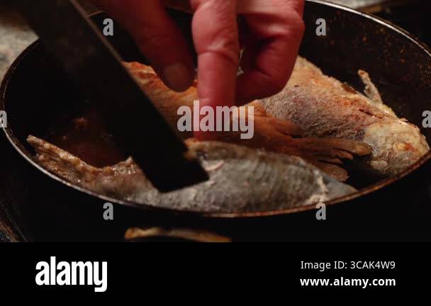 Home cooking. Woman frying river fish crucian carp in a frying pan with ...