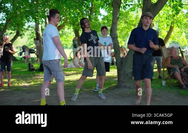 Outdoor public event, people dancing and relaxing under green trees in ...