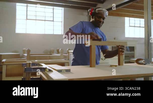 African American man sanding T-shaped frame after coworker pointing ...