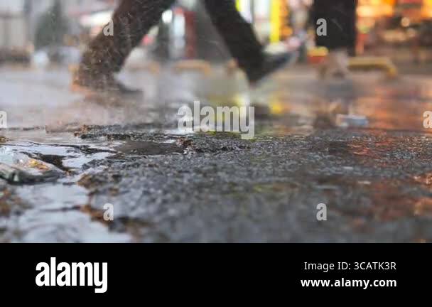 Pedestrians navigate a busy street as rain leaves glistening puddles ...