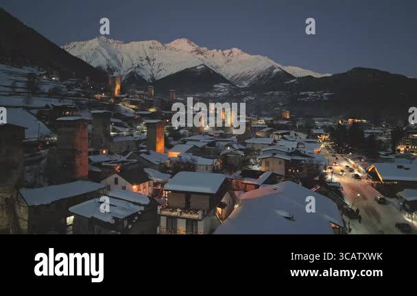 Aerial panning view snow covered Mestia village after sunset, glowing ...