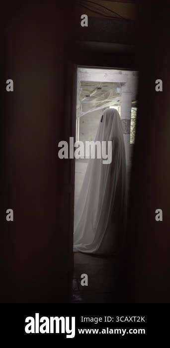 view through doors halloween ghost in white sheet standing in abandoned ...