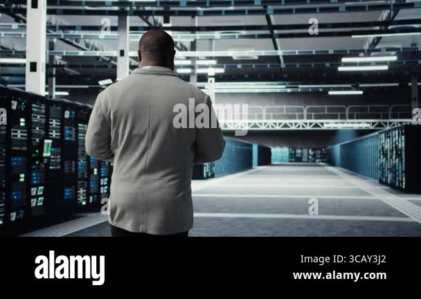 Technician walking in data center workplace with multiple rows of fully ...