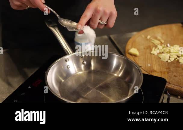 Coconut oil, spoonful adding, stainless pan. Close-up adding spoonful ...